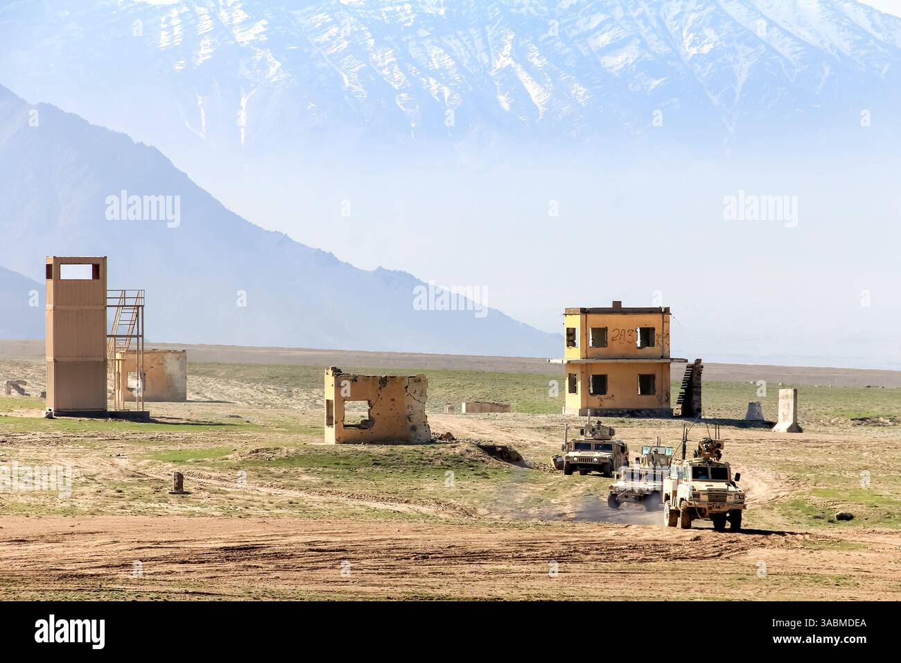 A wide view of military vehicles traversing an expansive desert terrain ...