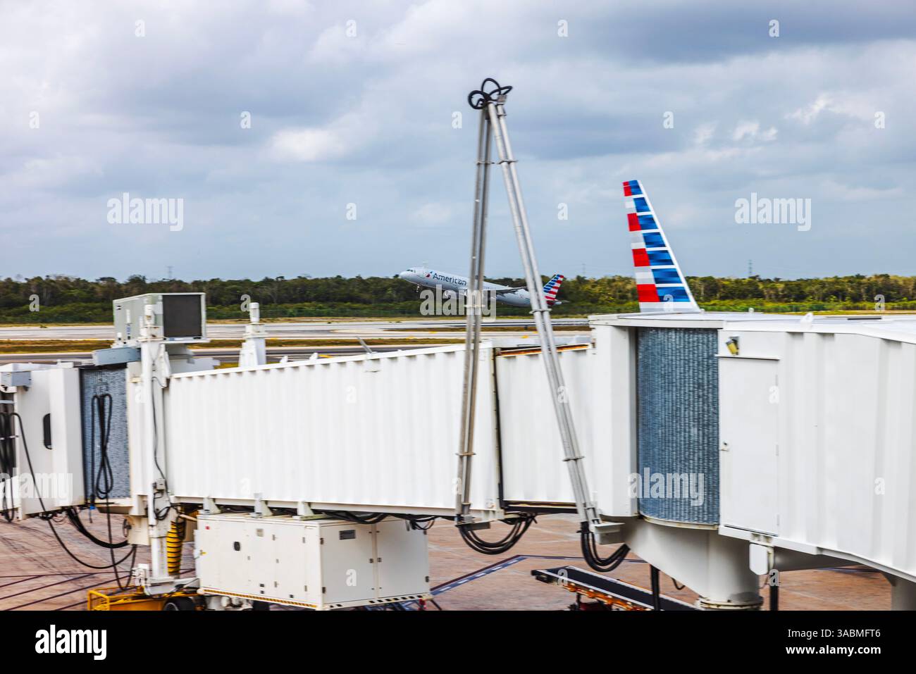 American Airlines airplane taking off behind passenger boarding bridge ...