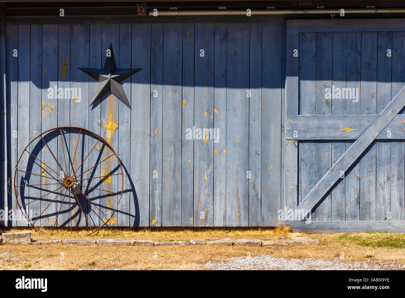 Close up of an outdoors side wall of a barn with a iron wheel and metal ...