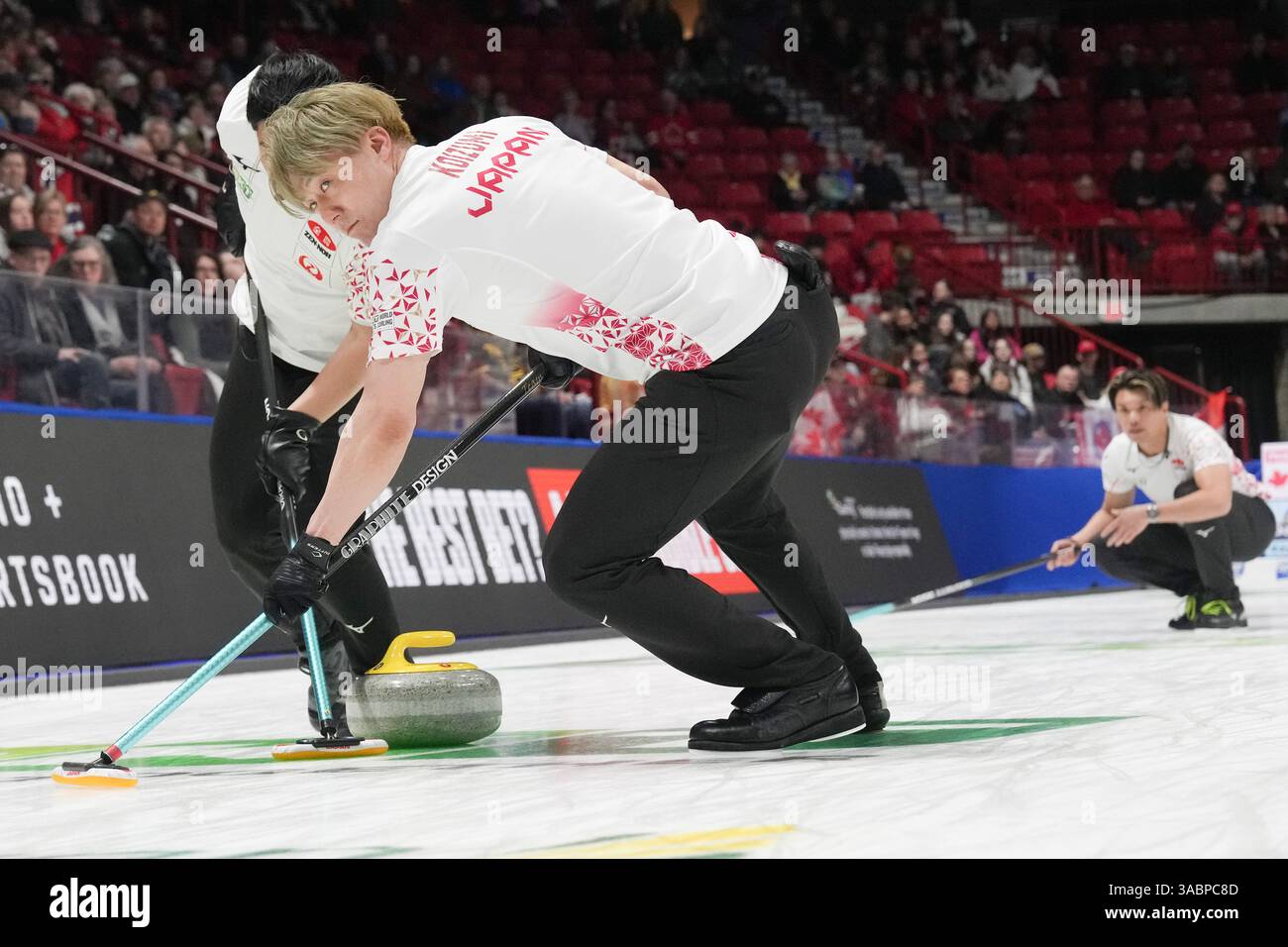 Japan's Satoshi Koizumi and Shingo Usui (obscured) sweep a stone for ...