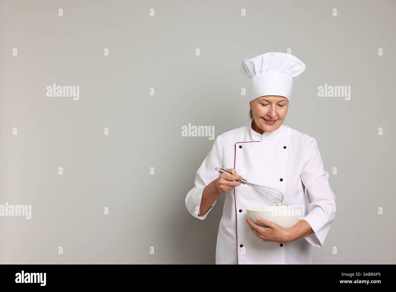 Professional pastry chef cooking on light grey background. Space for ...