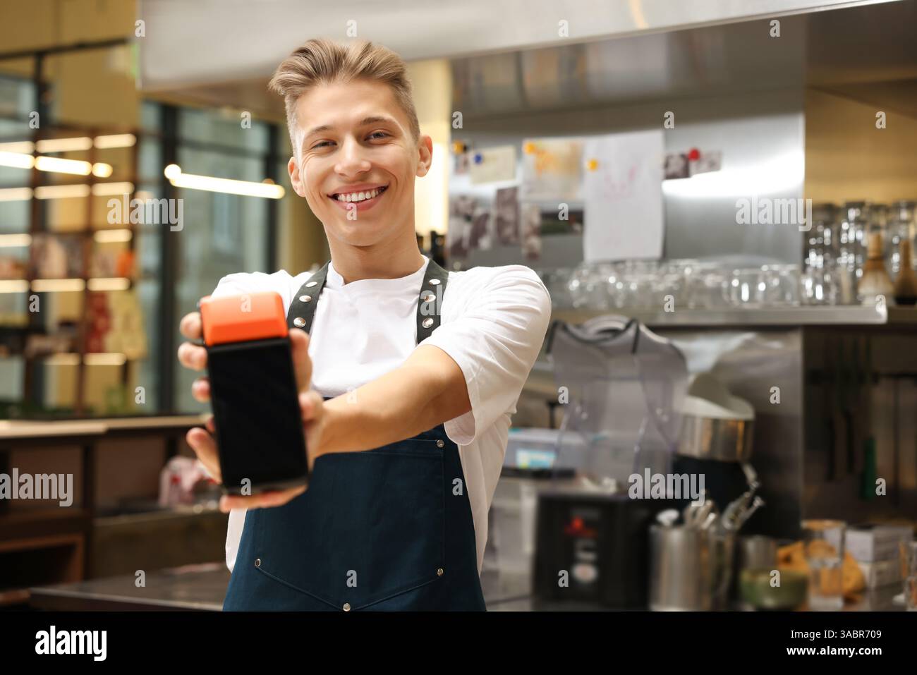 Smiling cafe worker with payment terminal indoors Stock Photo - Alamy