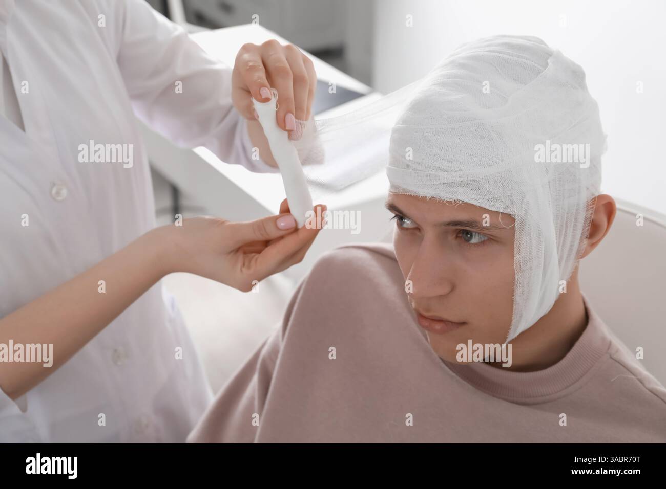 Doctor bandaging patient's head in clinic, closeup Stock Photo - Alamy