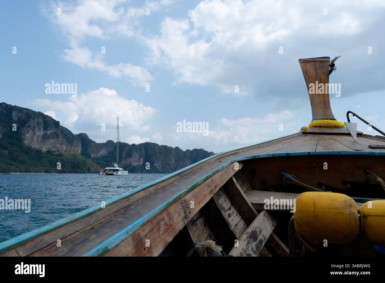 Traditional longtail boat heads towards a catamaran along Krabi’s ...