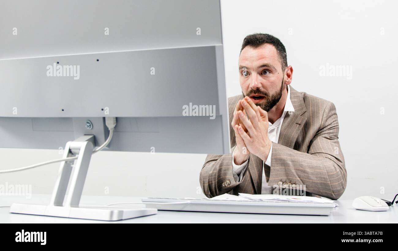 Tired, focused business man working at a computer in a bright office ...