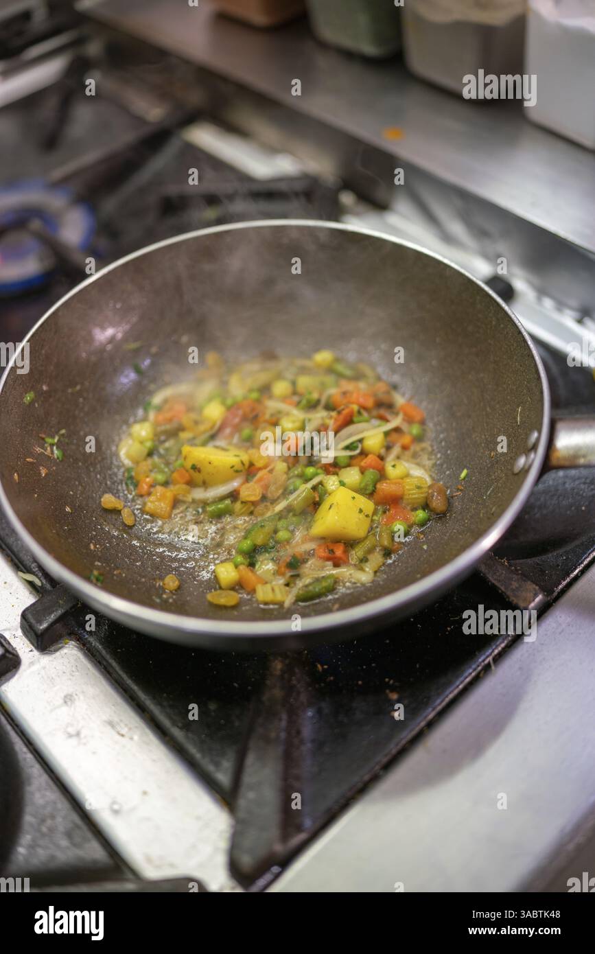 Indian chef preparing vegetable curry with potatoes, peas, carrots ...