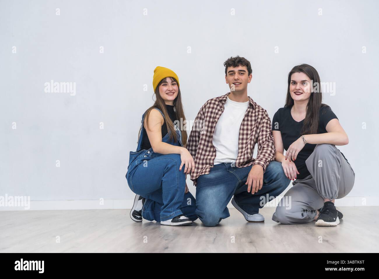 Three young dancers crouching in a dance studio, showcasing their ...