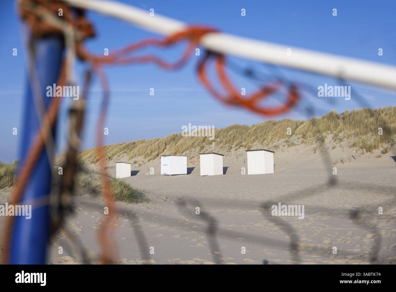 View through a volleyball net onto white beach houses surrounded by ...