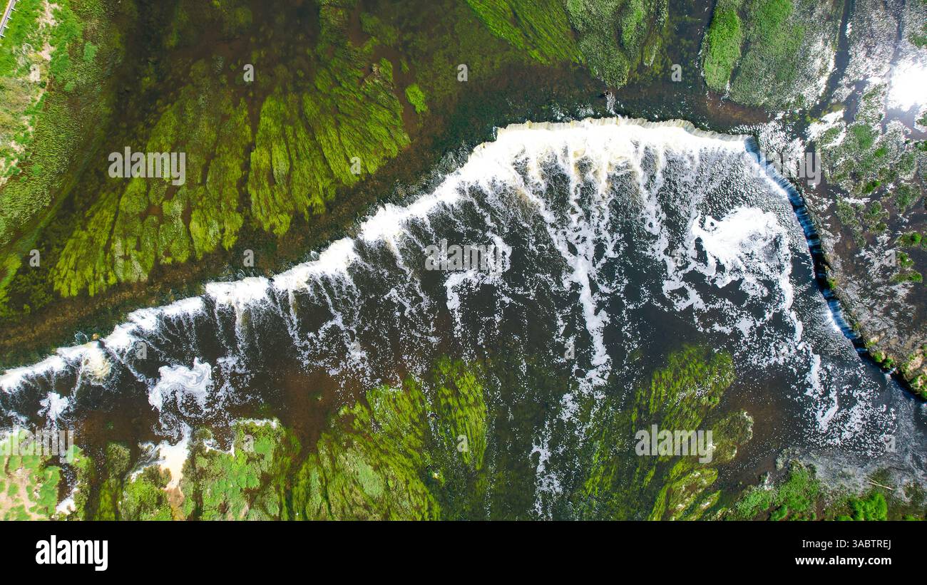 Aerial Top-Down View of a Waterfall Flowing Over Lush Green Riverbed ...