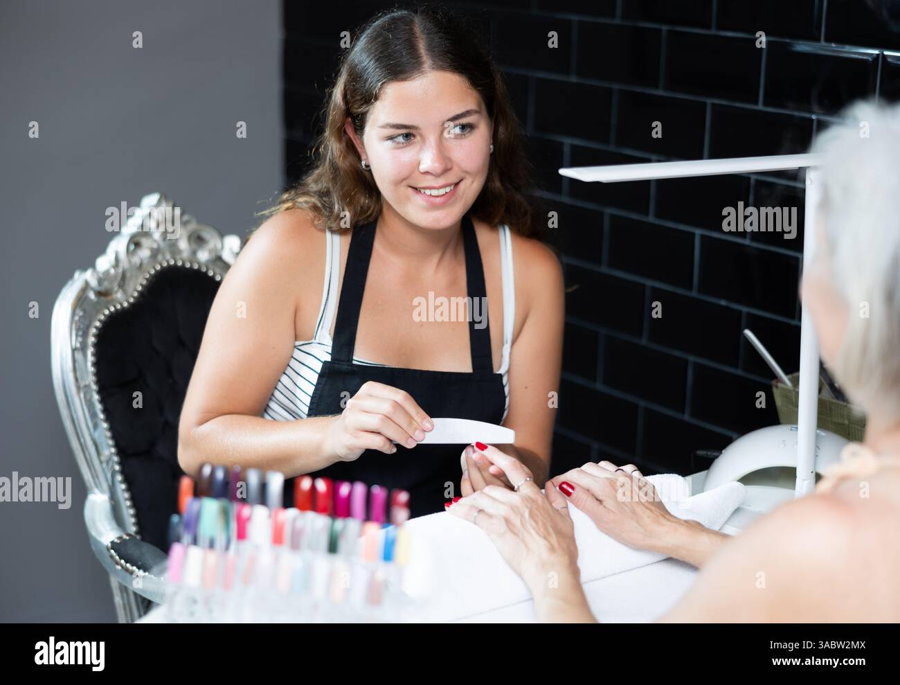 Skilled woman manicurist filing and shaping nails of female client ...