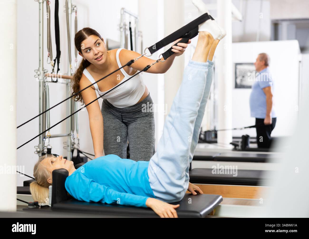 Experienced personal female trainer controlling movements of mature ...