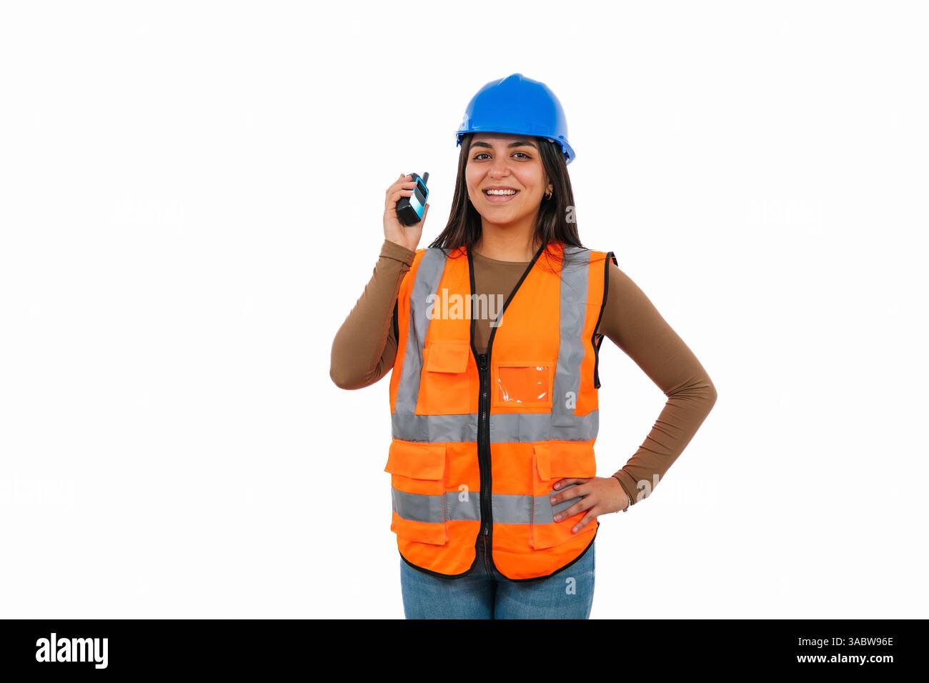 Young female engineer wearing safety vest and helmet, holding walkie talkie and smiling ...