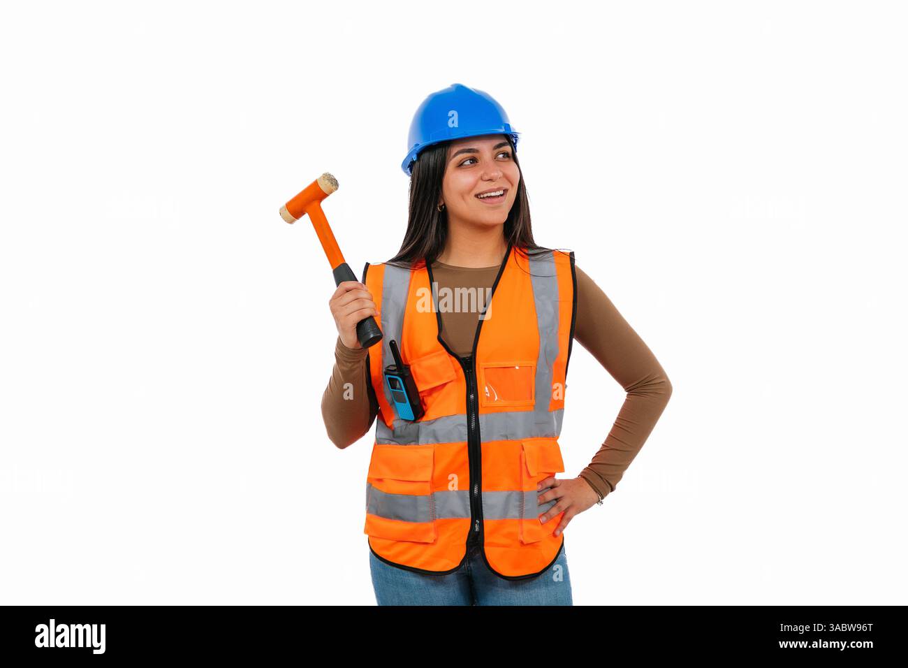 Young construction worker woman wearing safety vest and helmet holding hammer and walkie-talkie ...