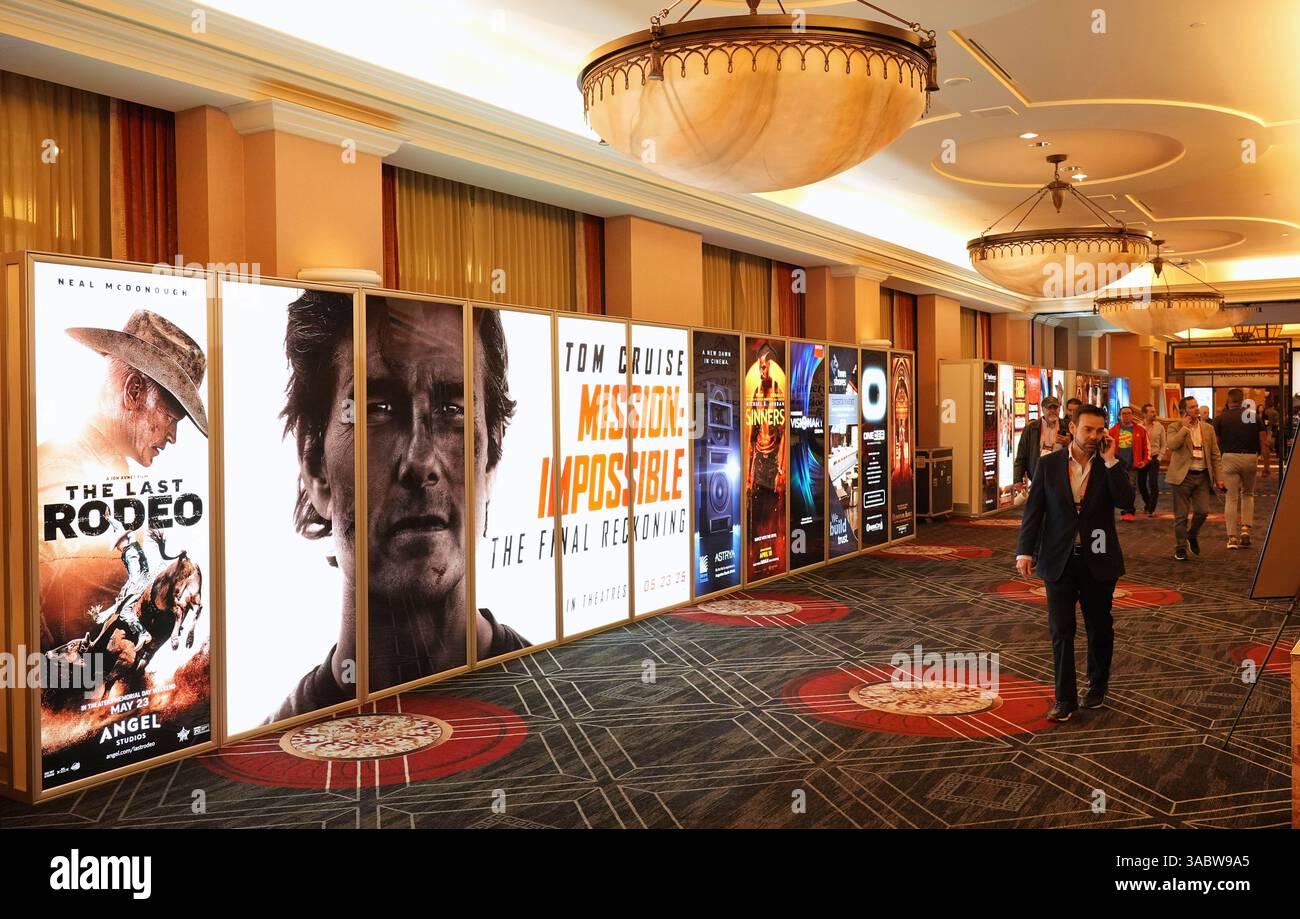 A CinemaCon attendee walks by advertisements for upcoming films at ...
