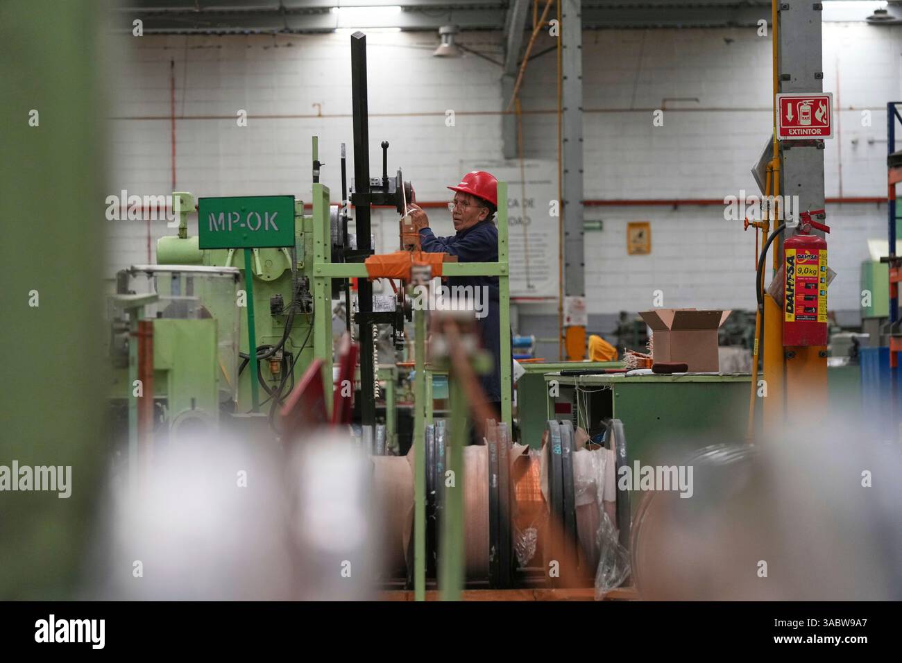 A worker cuts cables at an electric engine plant in Mexico City ...