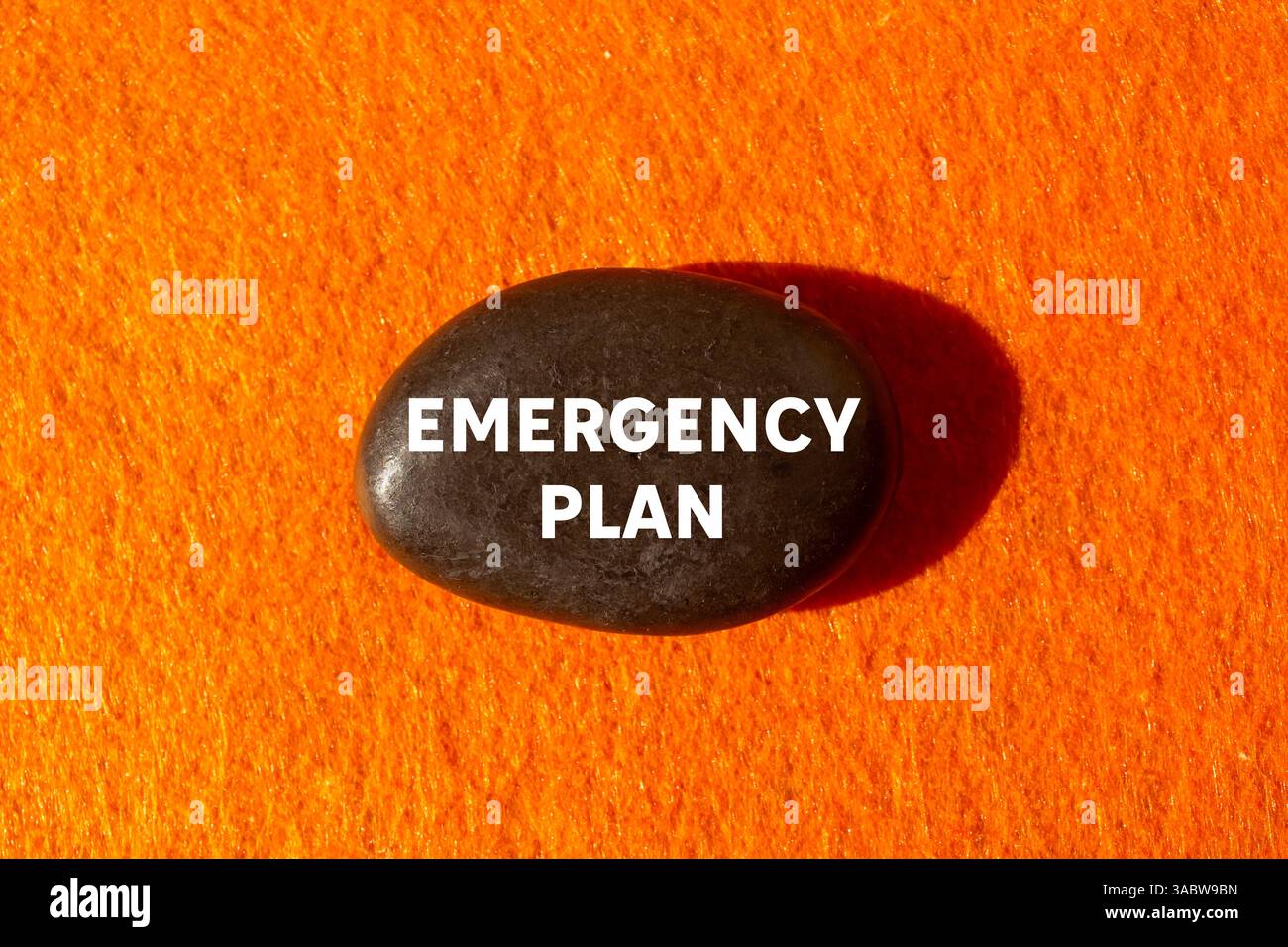 Emergency plan message written on black stone on orange background ...