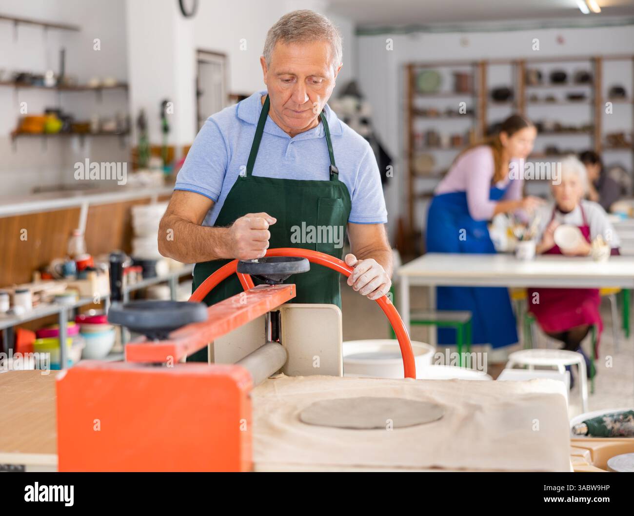 Old man rolling piece of clay on special machine - craft machine clay ...