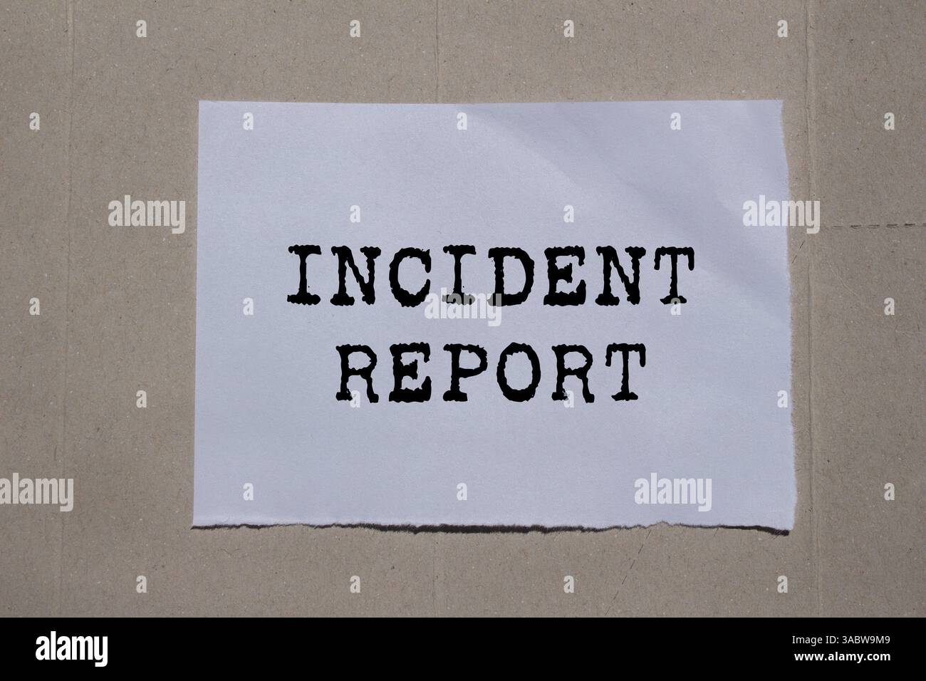 Incident report message written on ripped torn paper on cardboard background. Conceptual ...