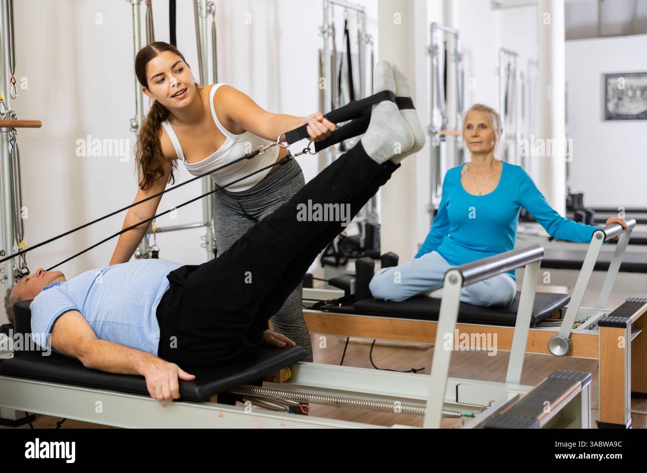 Mature man practicing Pilates system on reformer combo machine for ...