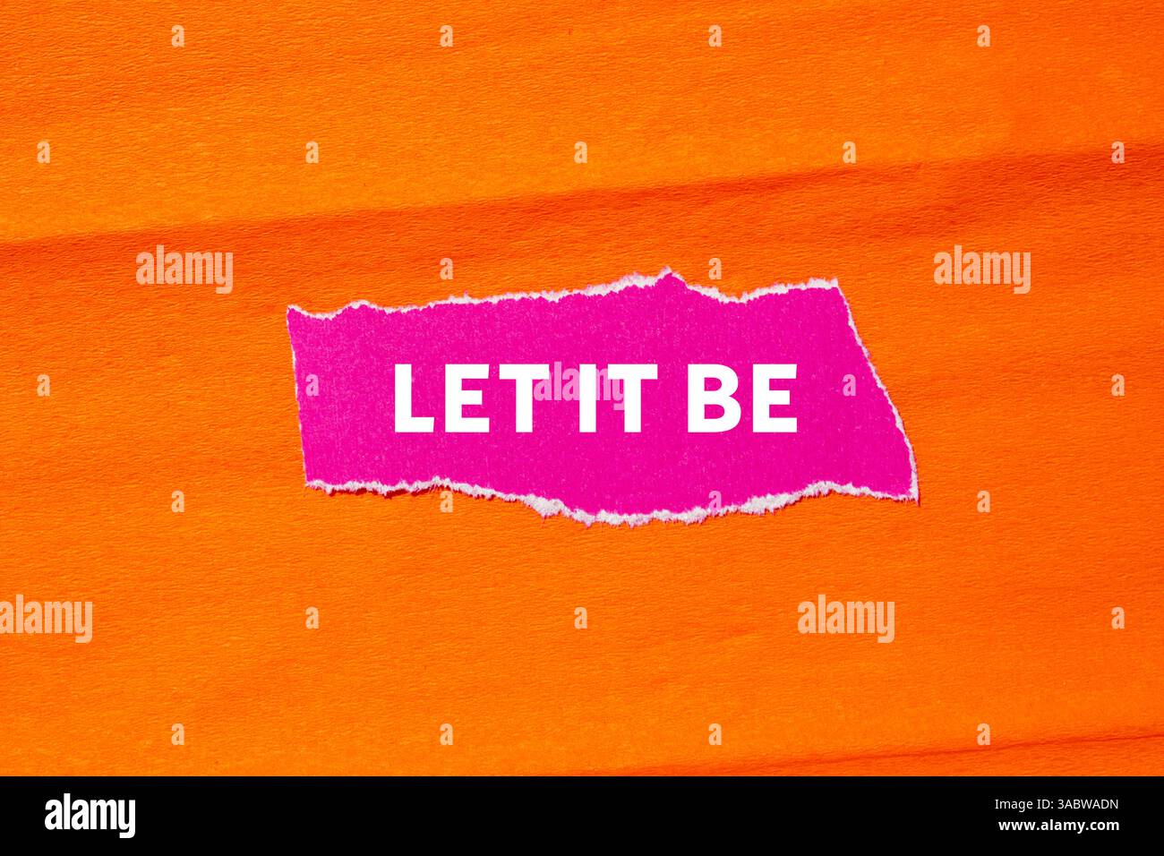 Let it be message written on ripped torn pink paper on orange ...