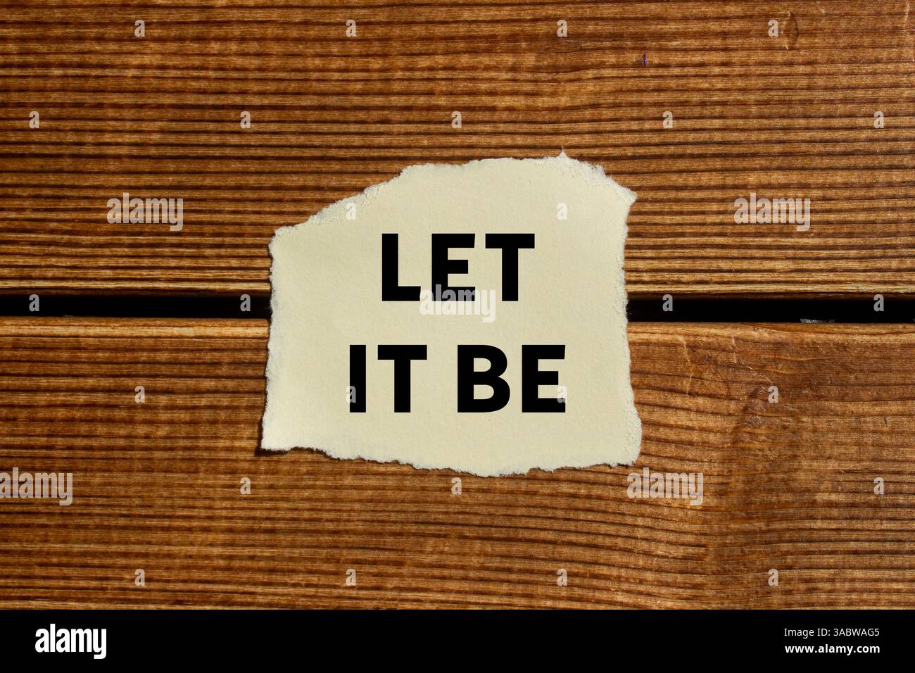 Let it be message written on ripped torn paper on wooden background ...