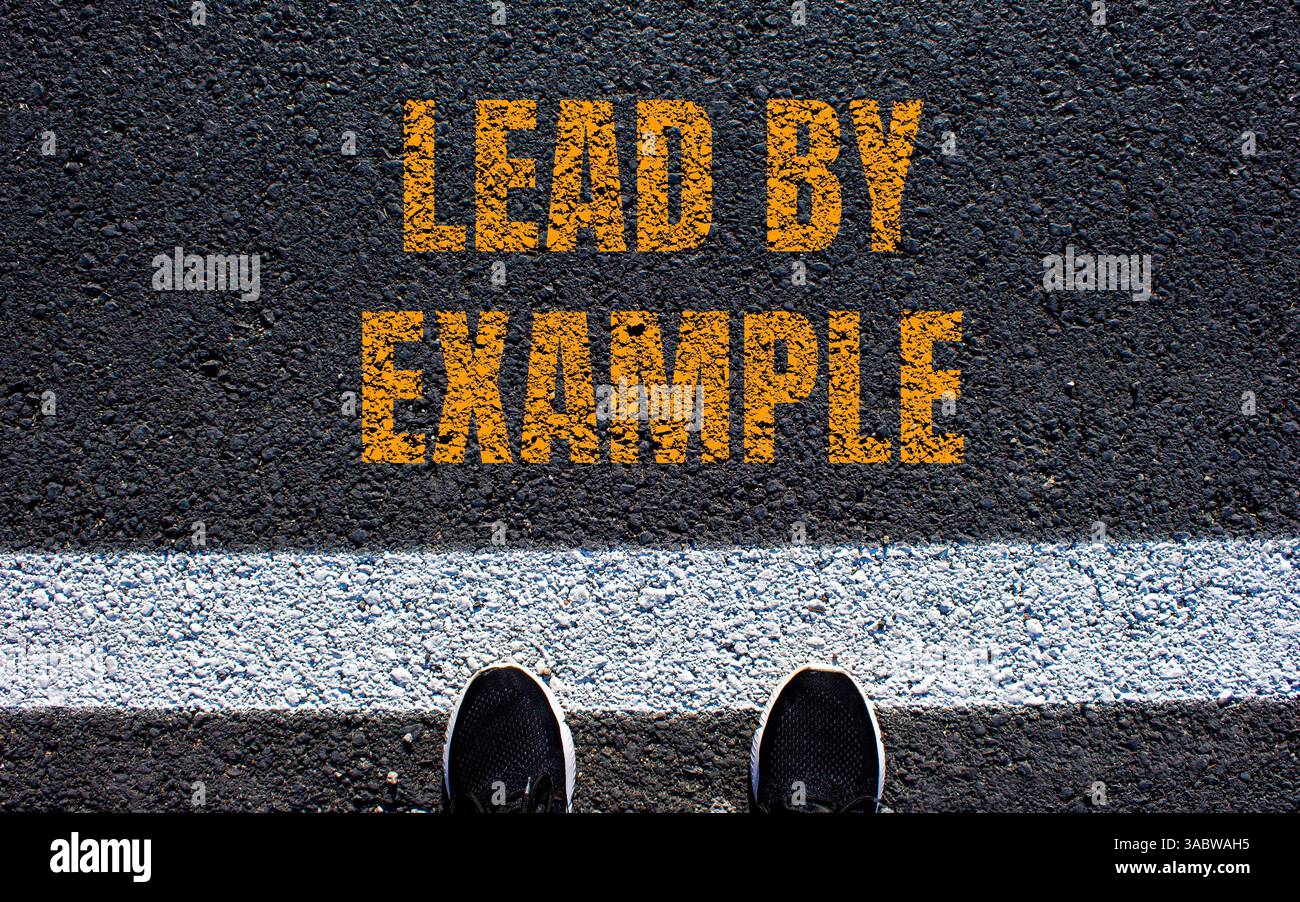 Lead by example message written on asphalt road. Conceptual lead by ...