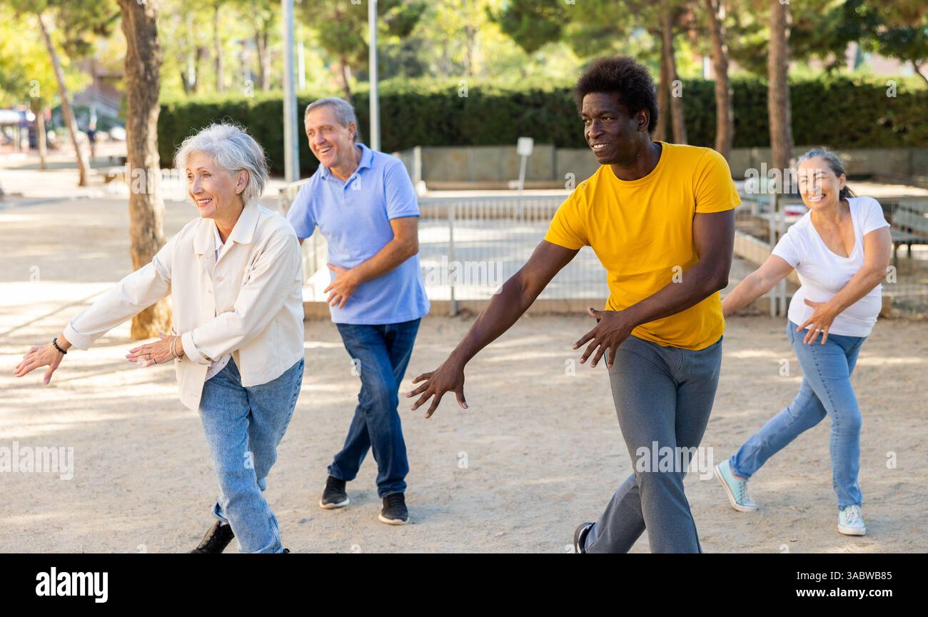 Positive mature women and men practicing vigorous dance movements in ...