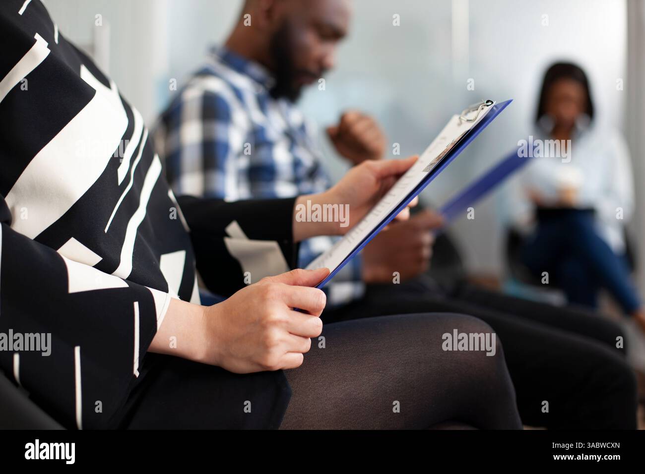 Selective focus on a woman holding a clipboard, seated in an office ...
