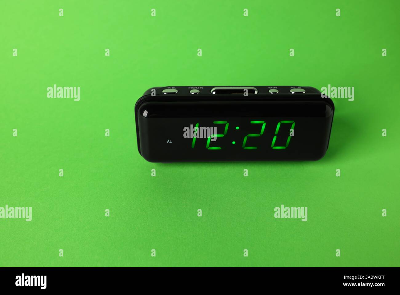 Digital alarm clock showing 12:20 o'clock on green background, space ...