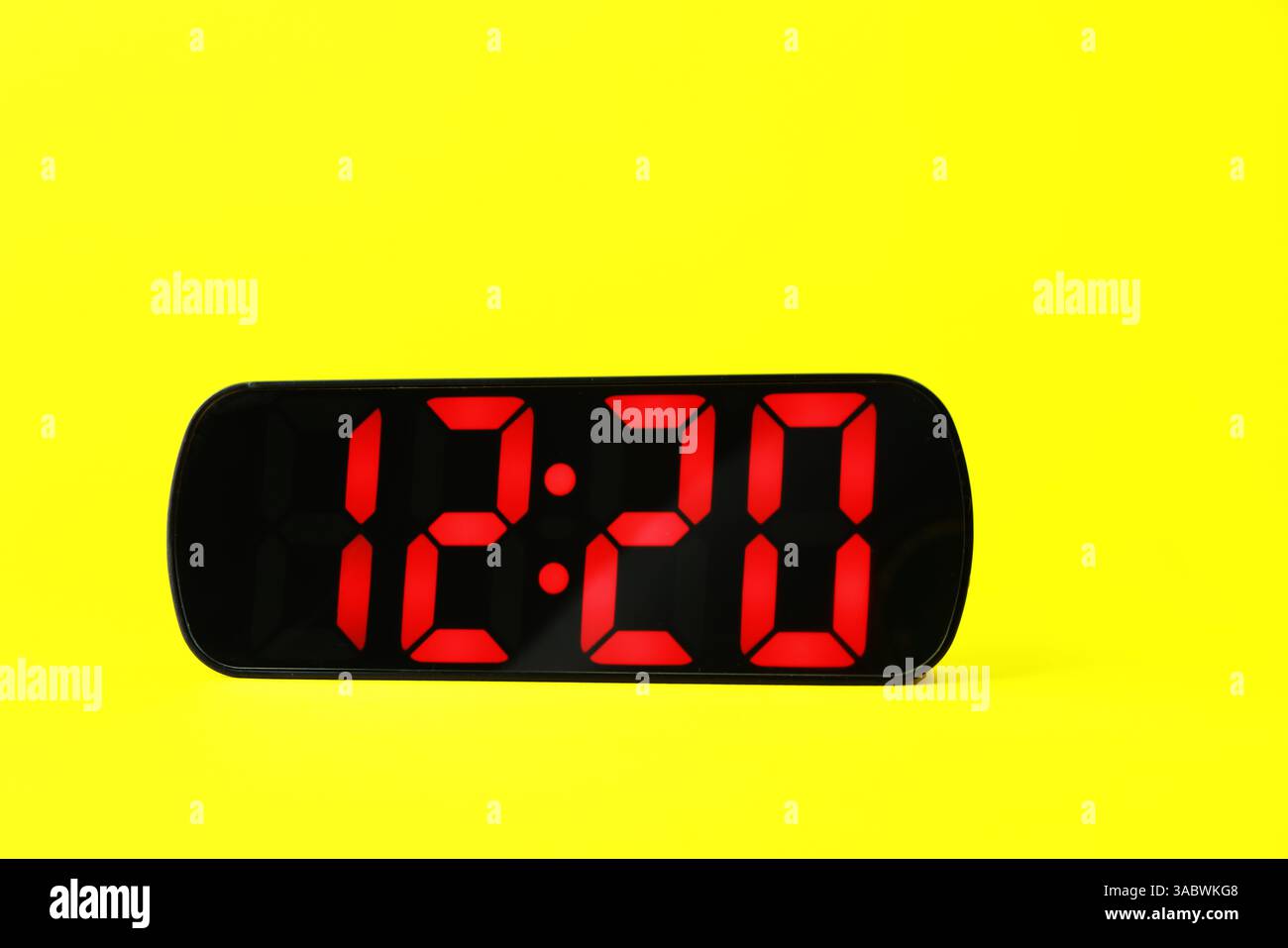 Digital alarm clock showing 12:20 o'clock on yellow background Stock ...