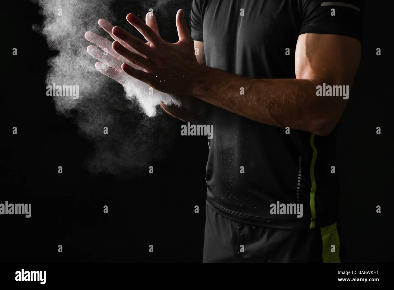 Man clapping hands with talcum powder before training on black ...