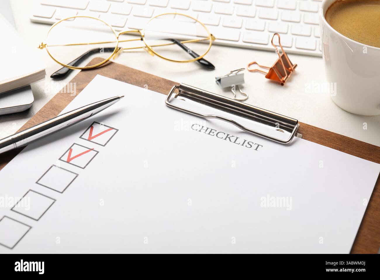 Checklist with marked checkboxes, stationery, glasses, coffee and ...