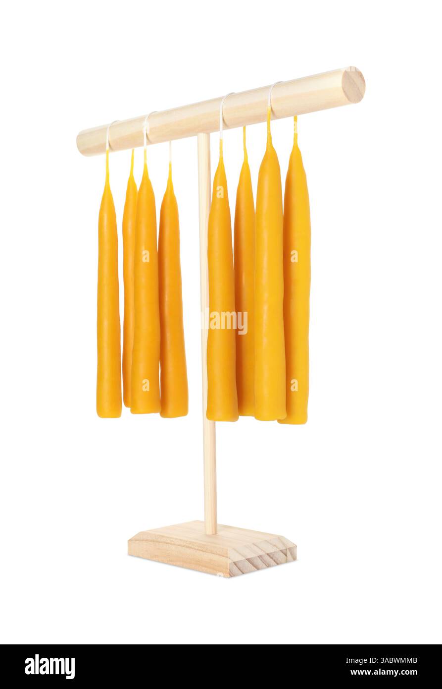Hand dipped beeswax candles drying on rack against white background ...