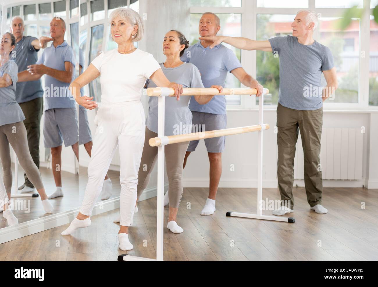 Diligent mature men and women practicing basic positions with trainer ...