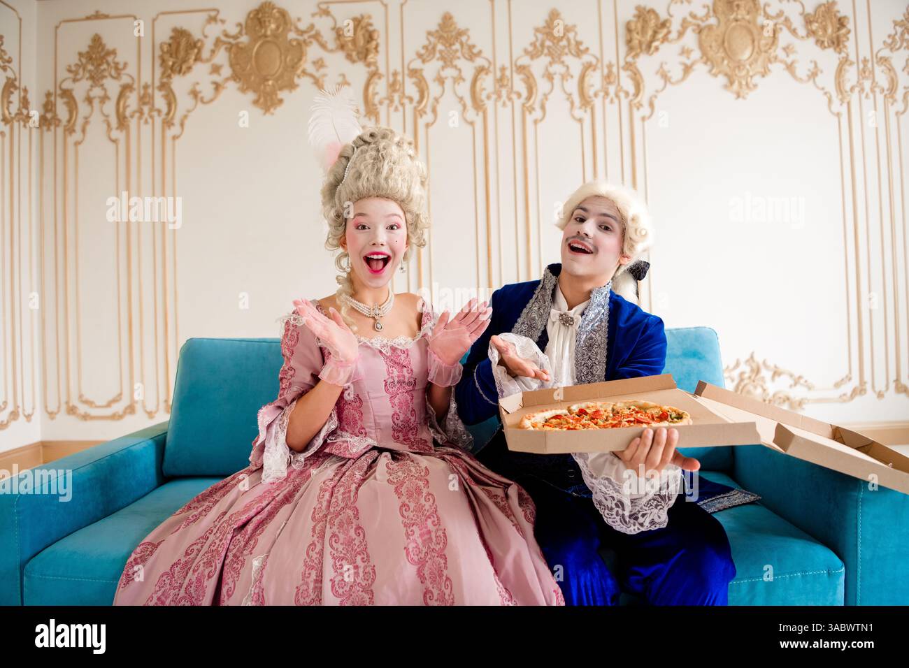 Aristocratic couple in baroque attire enjoy pizza together in a lavish ...