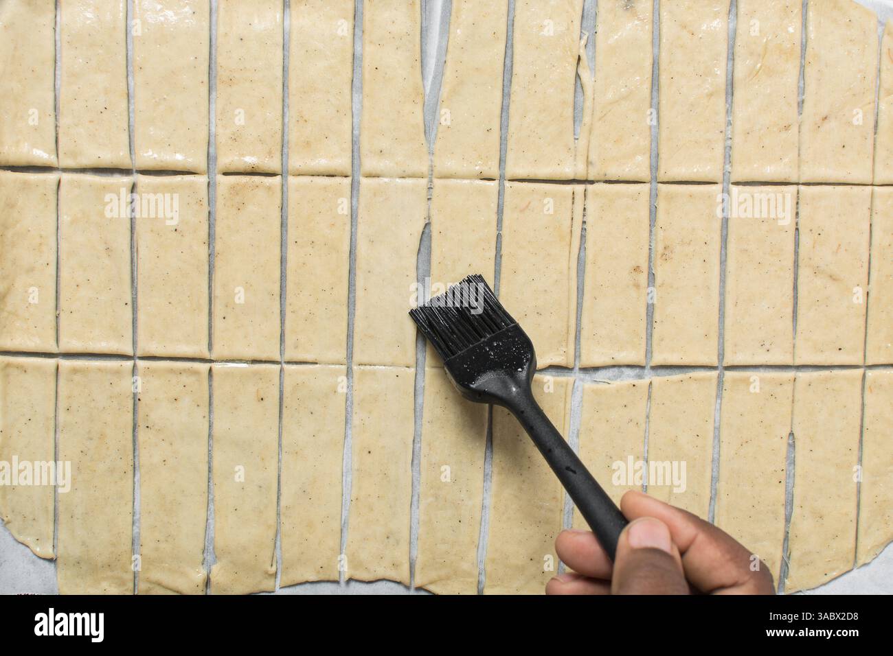 Overhead view of crackers dough on parchment paper being sliced ...