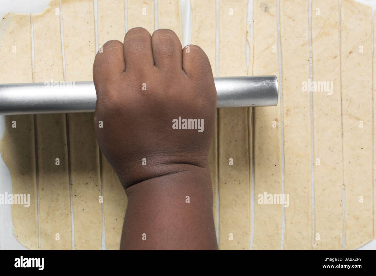 Overhead view of crackers dough on parchment paper being sliced ...