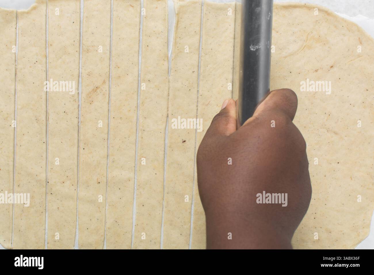Overhead view of crackers dough on parchment paper being sliced ...