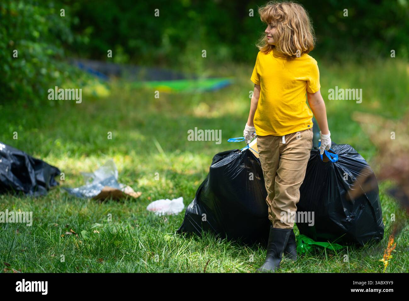 Environment plastic pollution. Volunteer kid collecting trash in the forest and holding a ...