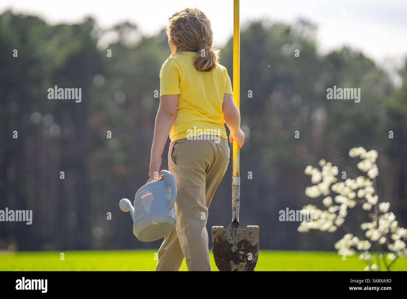 Child planting a tree in garden. Child digging soil with shovel and ...