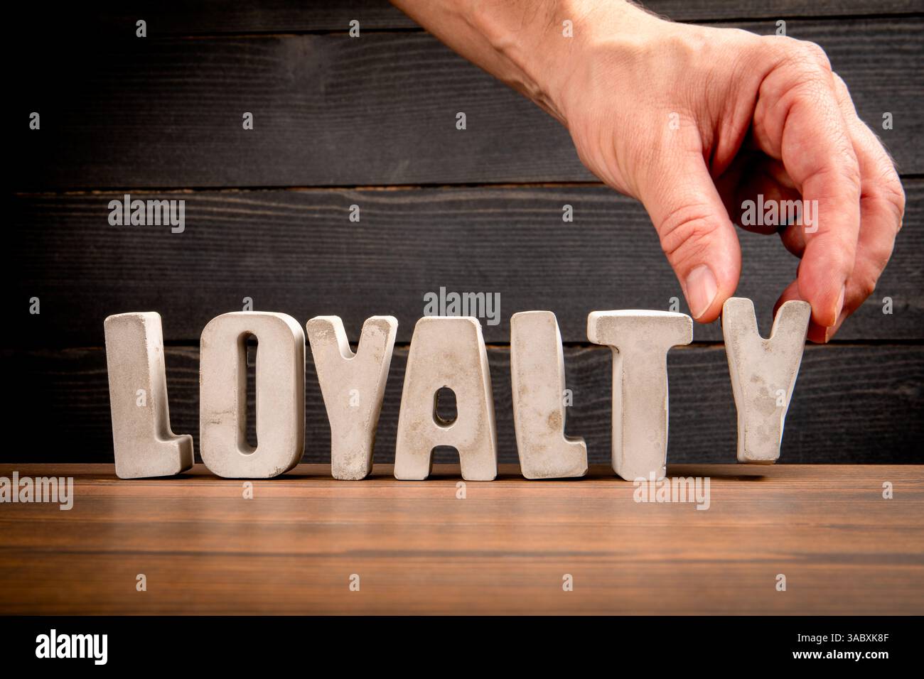 Hand Placing LOYALTY Text on Wooden Desk Stock Photo - Alamy