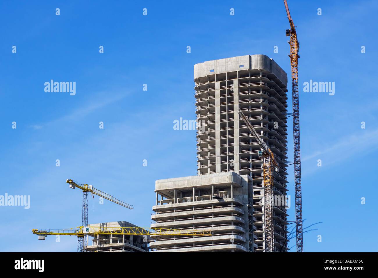 A tall building is currently undergoing construction, featuring cranes ...