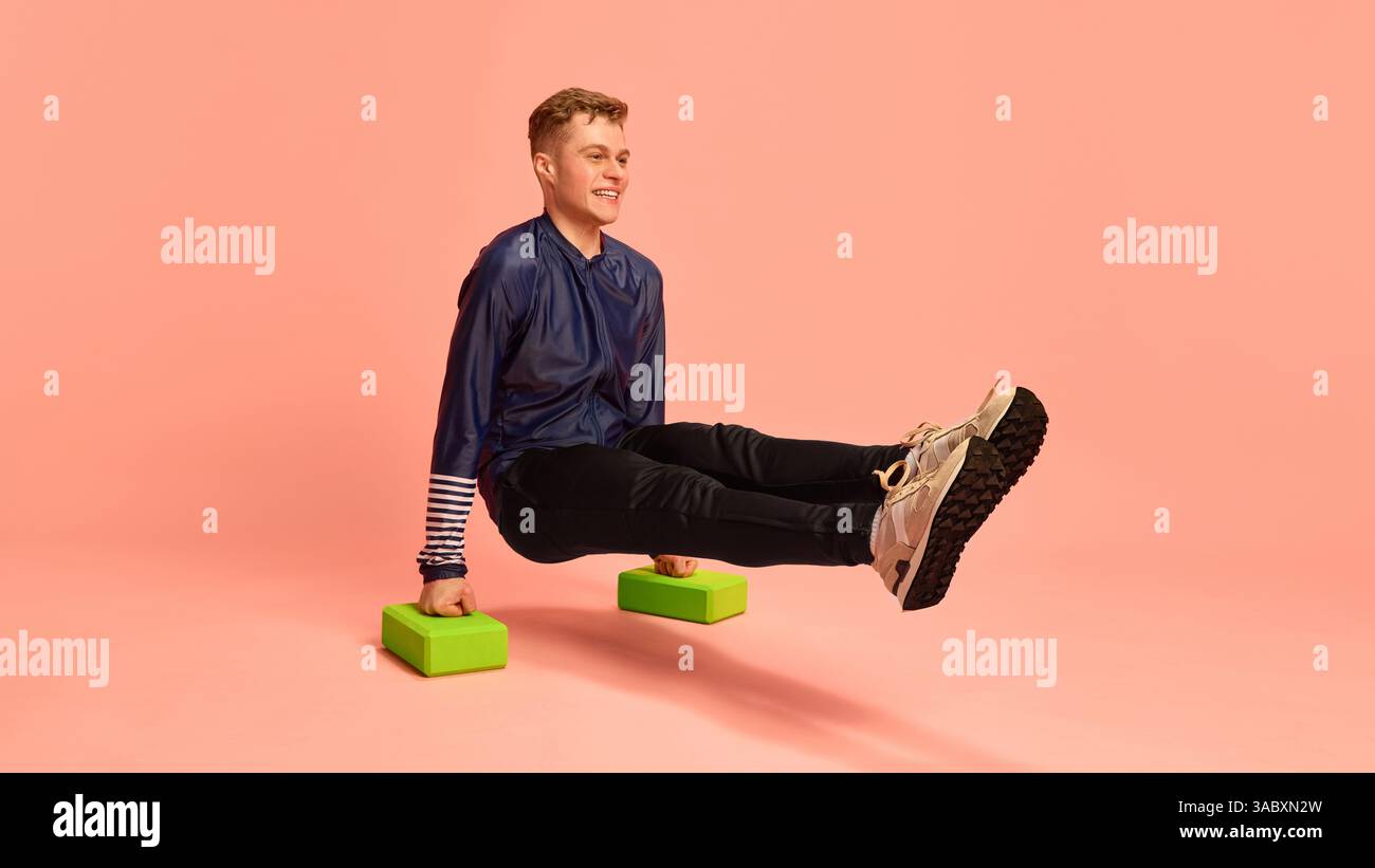 Young man performing elevated L-sit on foam blocks wearing blue ...