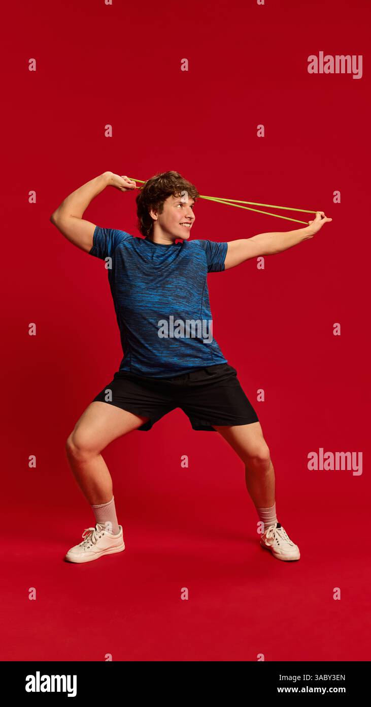 Man holding resistance band in archer pose, smiling during training ...
