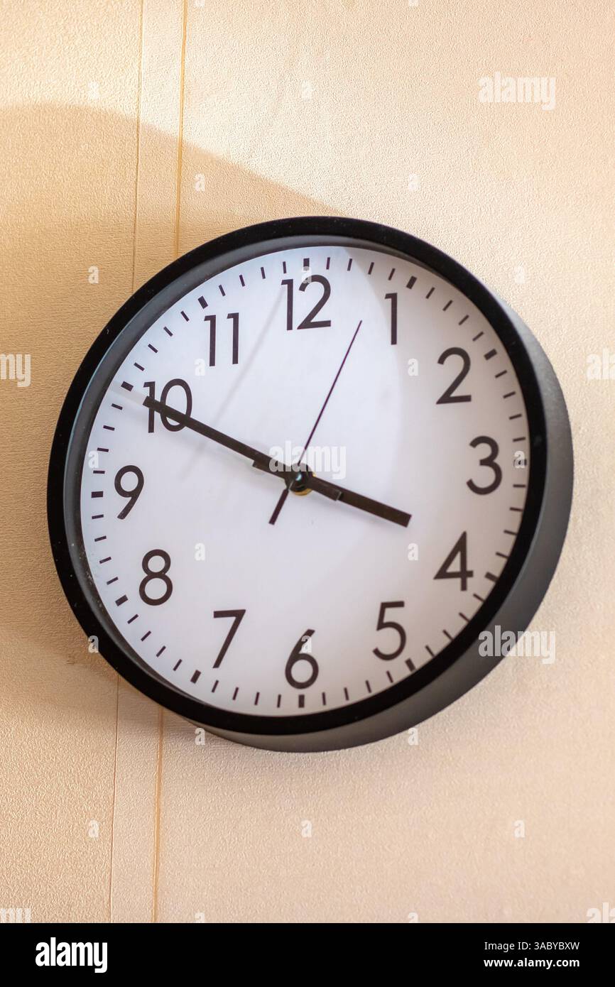 A classic black and white clock affixed to a wall indicates the time as ...