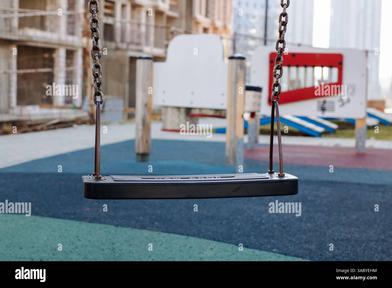 An empty swing sways gently back and forth in a vibrant and colorful ...