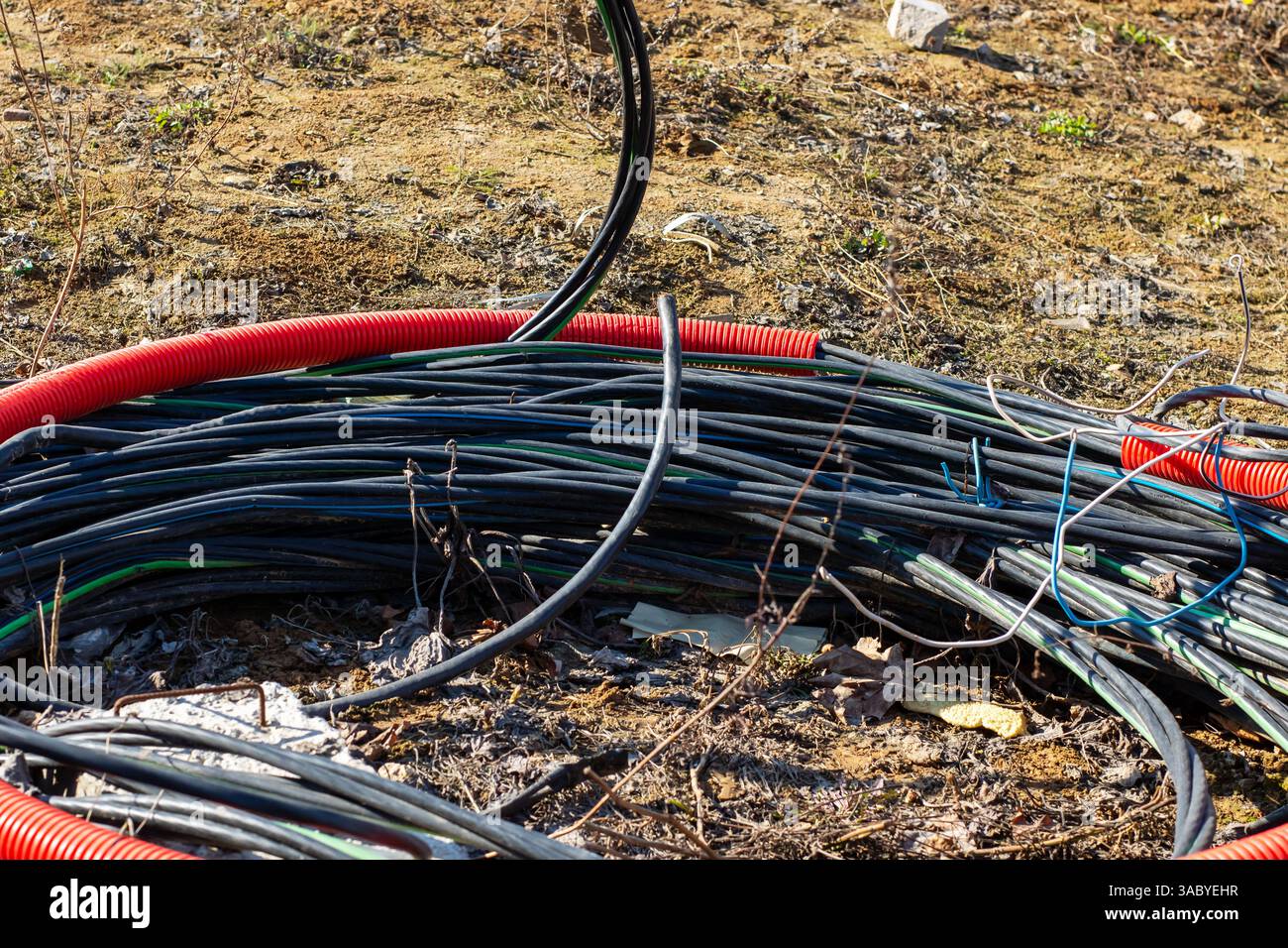 A close-up of coiled cables and wires resting on the ground, showcasing ...