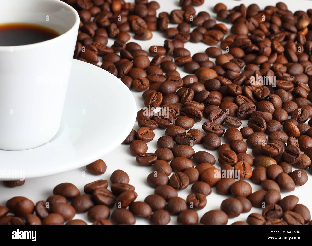 A steaming cup of black espresso coffee with roasted beans on a clean ...