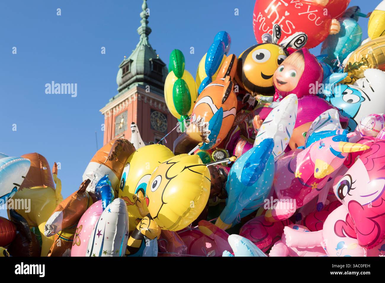 Poland, Warsaw, tourist balloons for sale and the clock tower of the ...