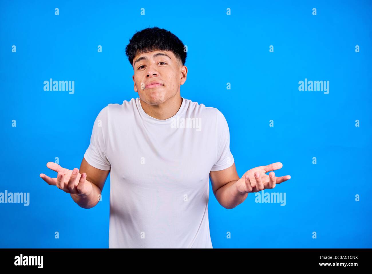 Uncertain young man shrugging with a confused expression, unsure about ...